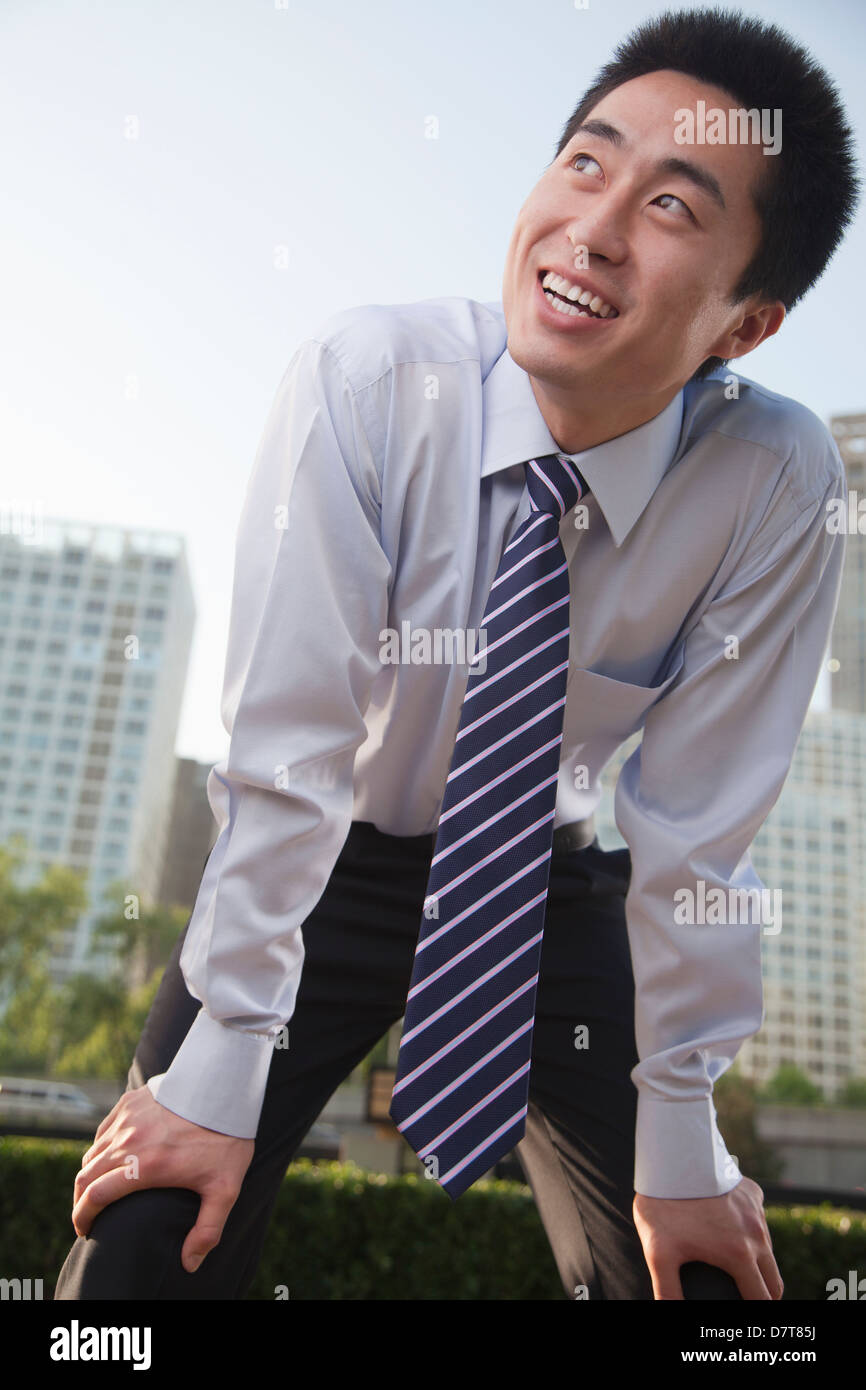 Young businessman bending forward, outside in the business district ...