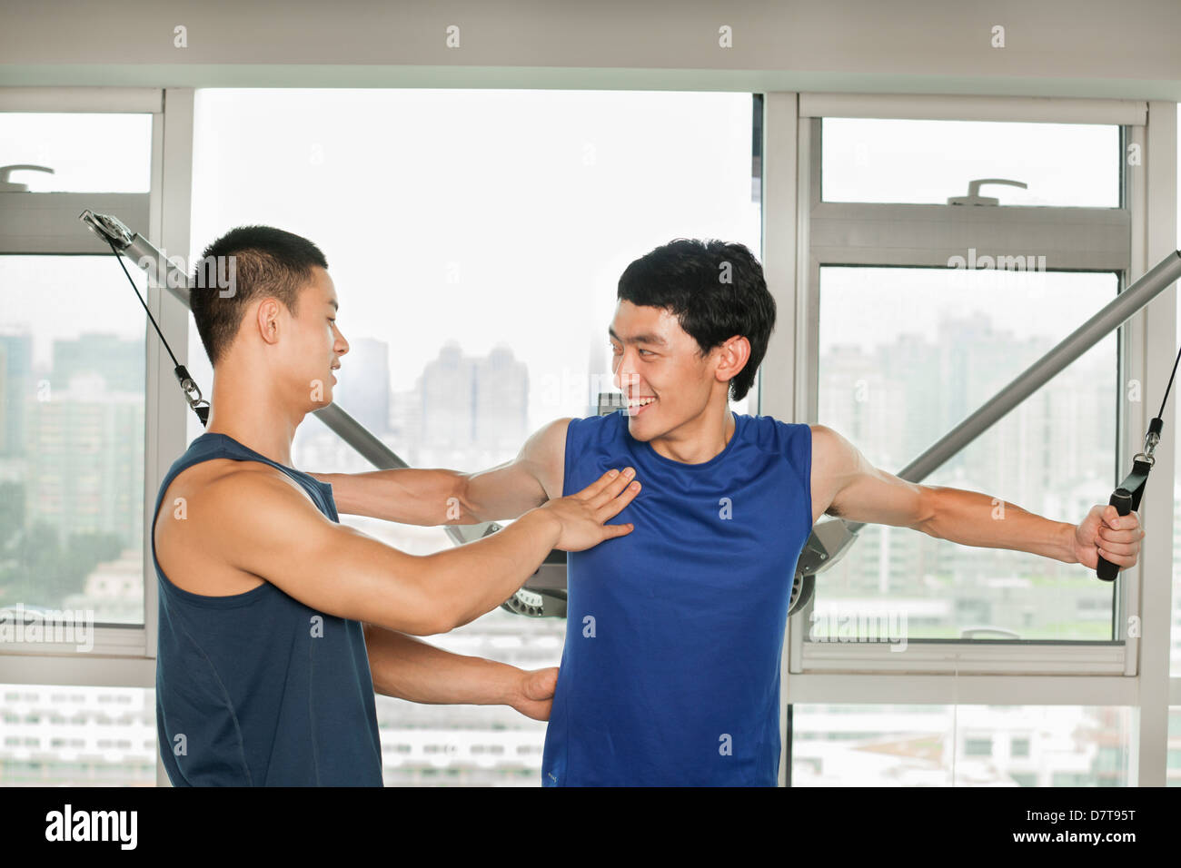 Young man exercising with his personal trainer in the gym Stock Photo ...