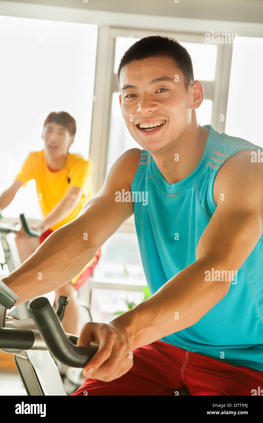 Young men on stationary bikes exercising in the gym Stock Photo - Alamy