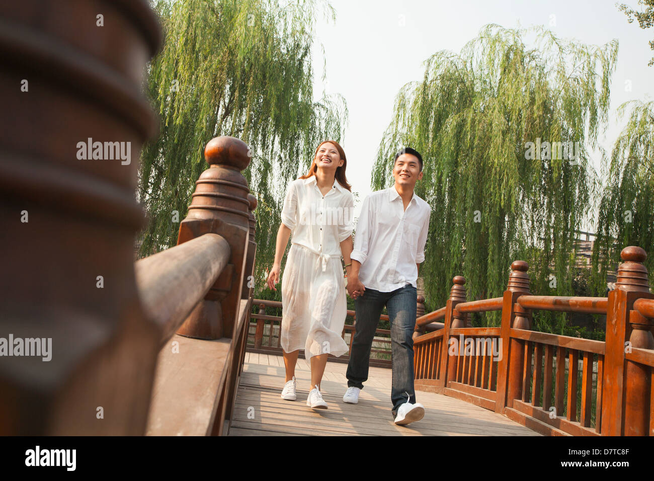 Young Couple Holding Hands and Crossing a Bridge Stock Photo - Alamy