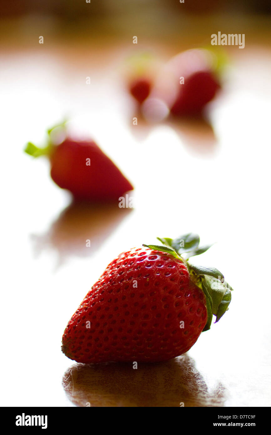 One main strawberry with others behind on a table Stock Photo - Alamy