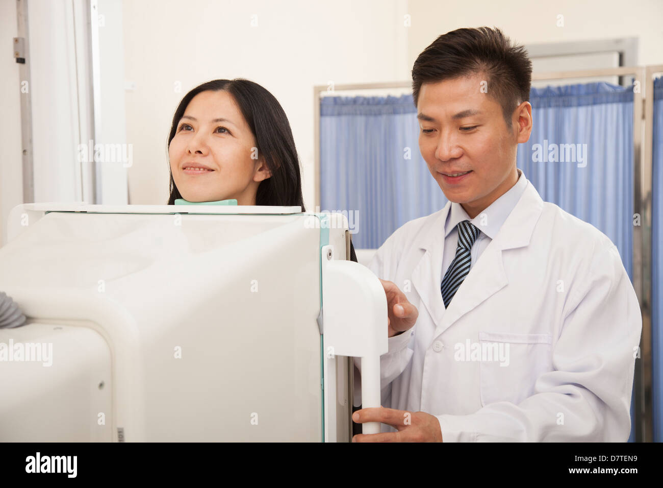 Male Doctor Examining Female Patient's Mid Section With X-ray Machine ...