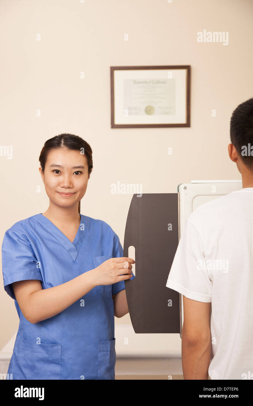 Female Doctor Examining Male Patient's Mid Section With X-ray Machine ...