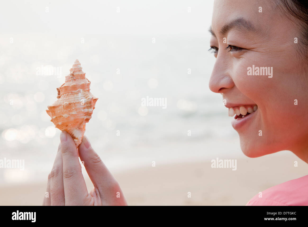 Young Woman Looking at Seashell Stock Photo - Alamy