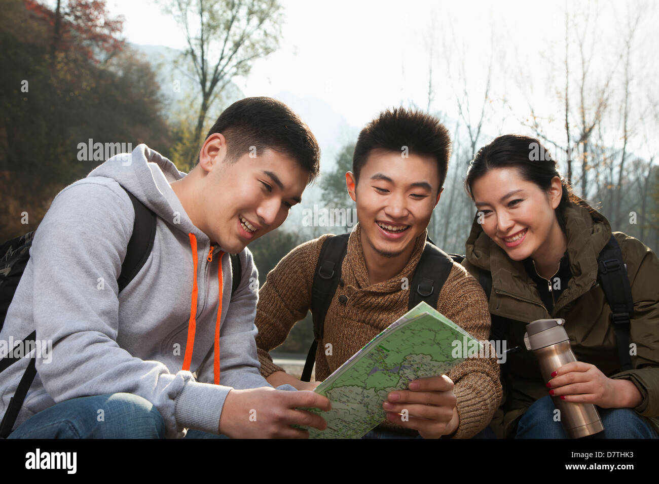 Friends sitting and looking at the map Stock Photo - Alamy