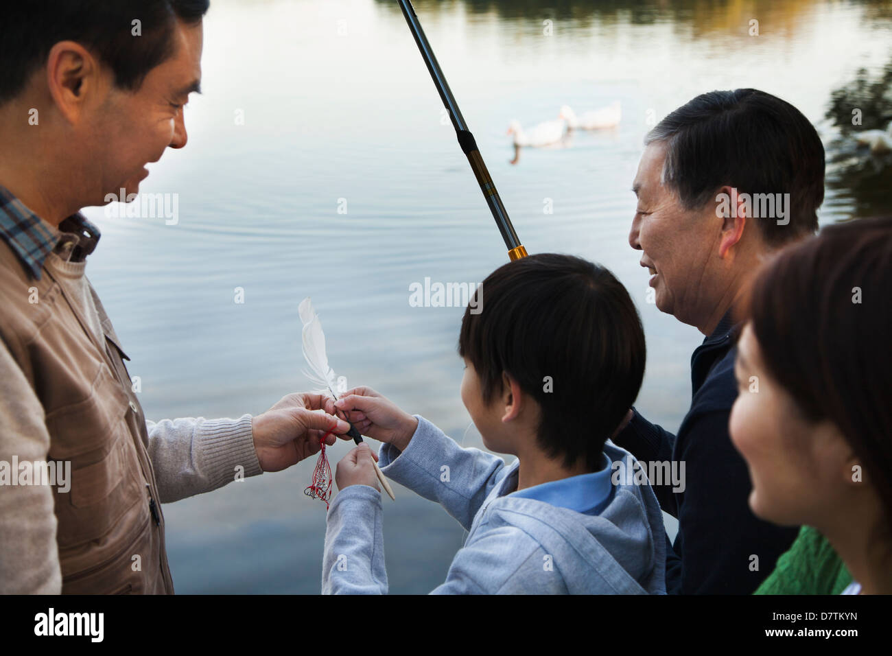 Family teaching a boy how to fish at a lake Stock Photo - Alamy