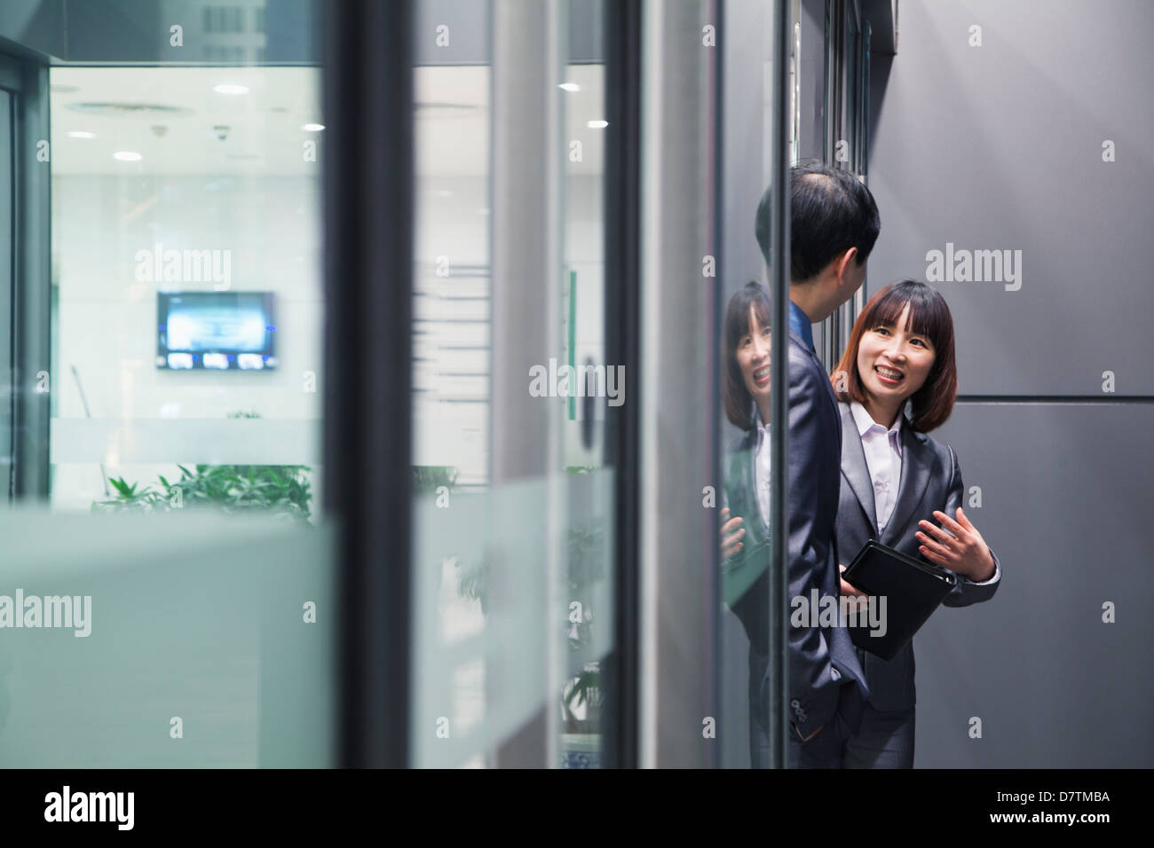 Business people talking together by a glass wall Stock Photo - Alamy