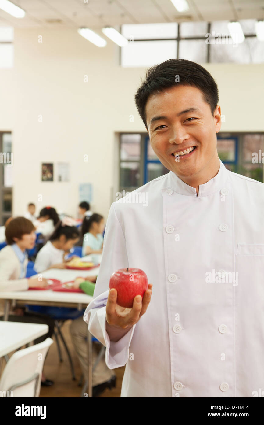 Chef portrait in school cafeteria holding apple Stock Photo - Alamy