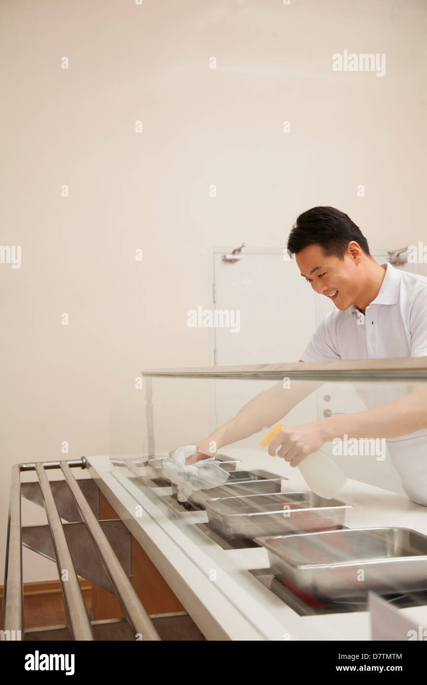 Cafeteria worker cleaning food serving area Stock Photo - Alamy