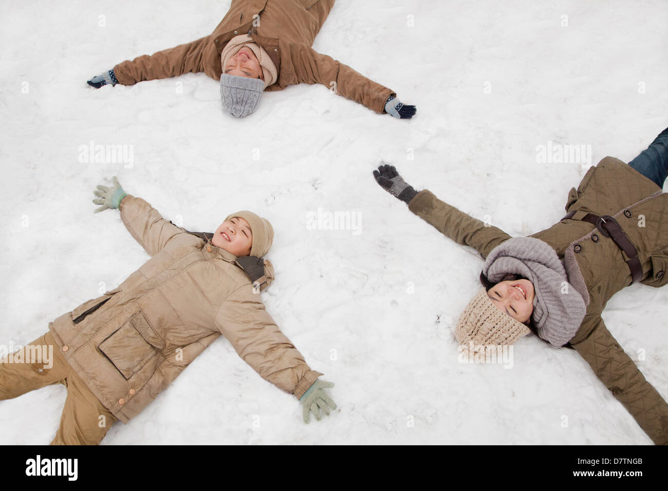 Family laying in snow making snow angels Stock Photo - Alamy