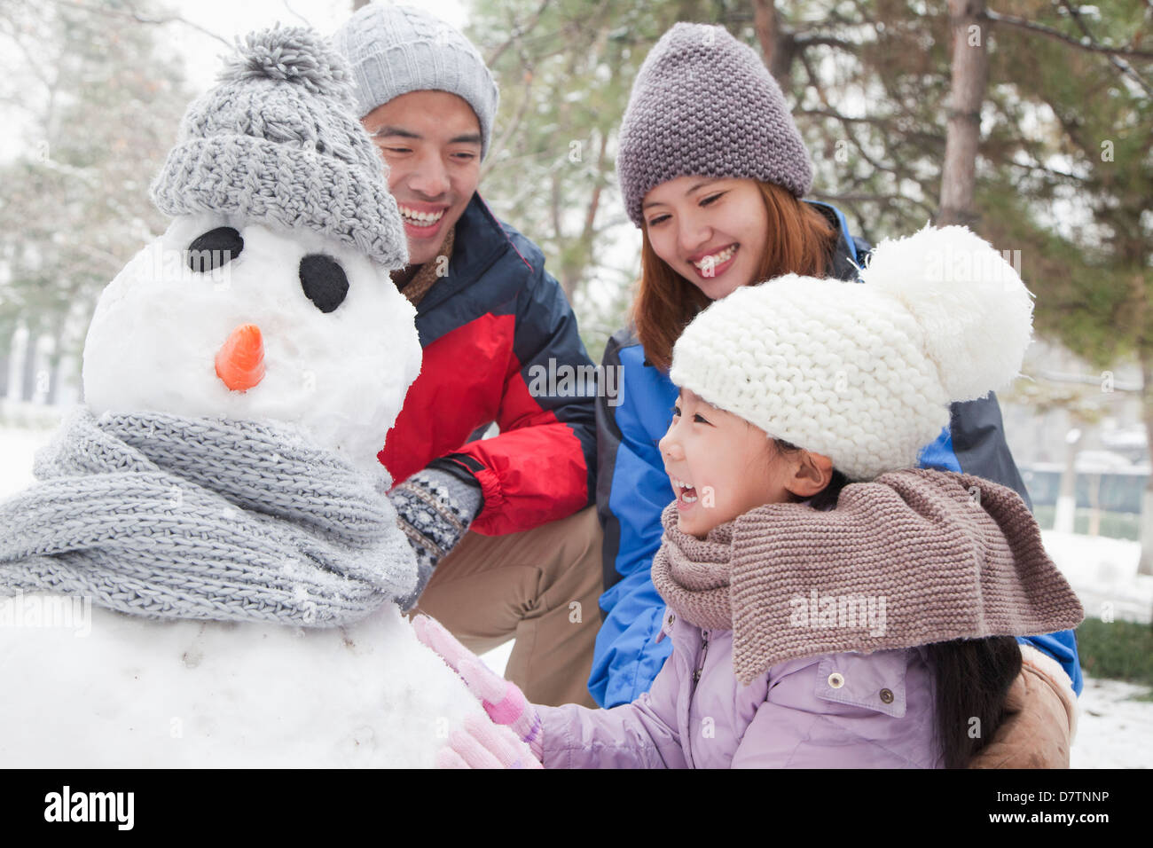 Family making snowman in a park in winter Stock Photo - Alamy