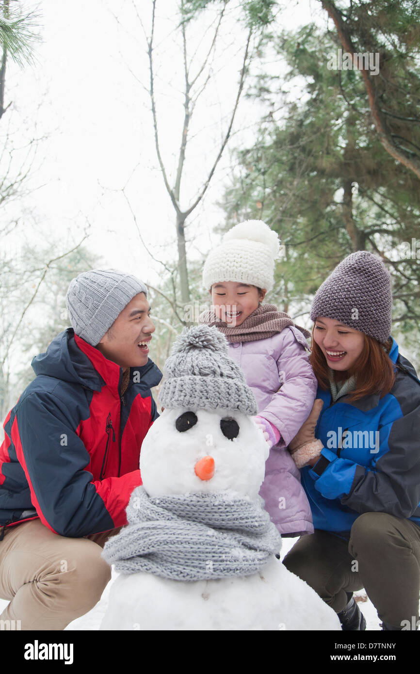 Family making snowman in a park in winter Stock Photo - Alamy
