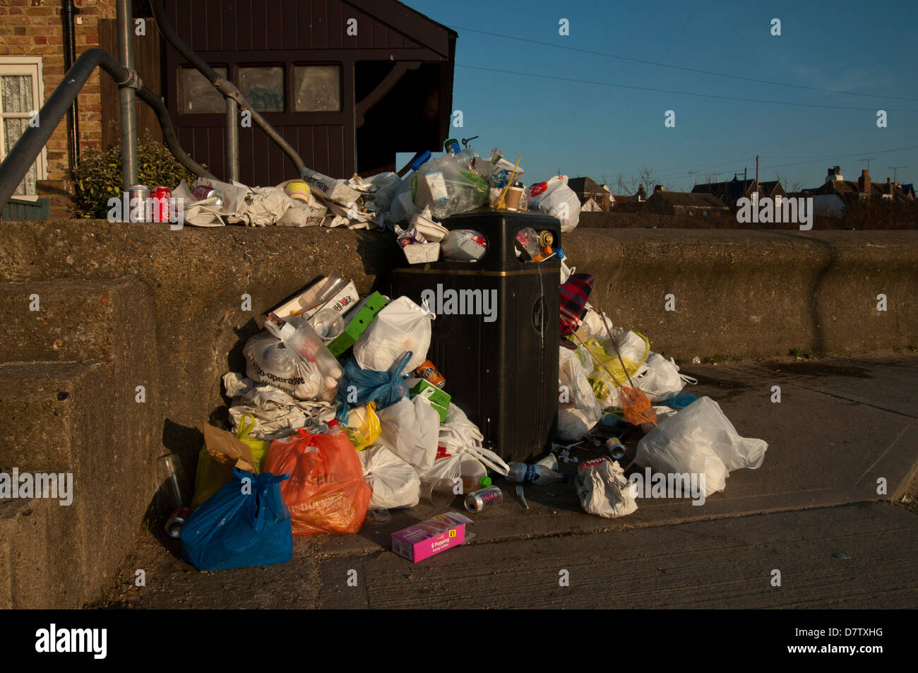 Over filled rubbish bin at the end of a busy day waste paper plastic ...
