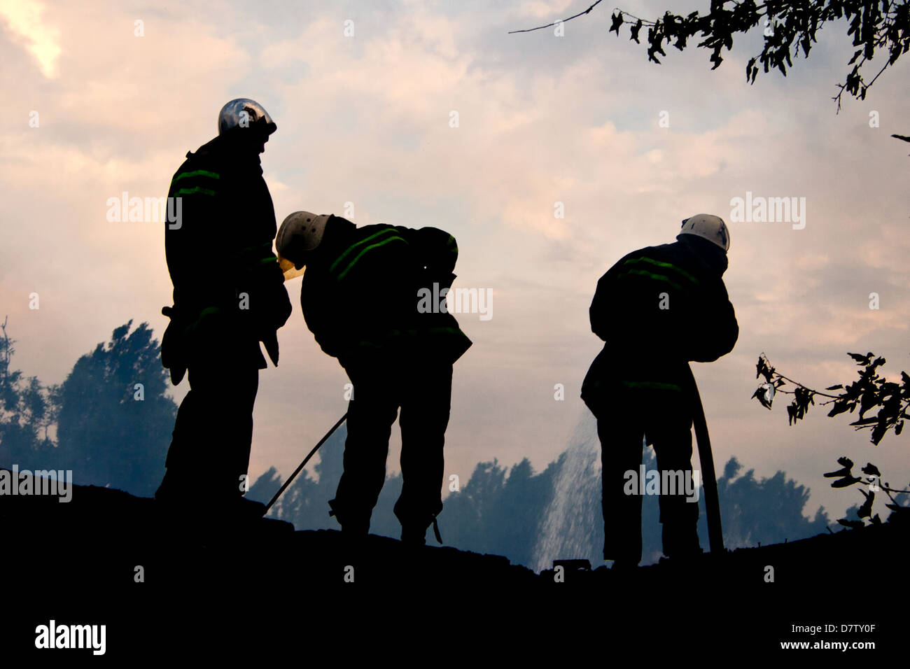 Smoldering remains of a ghetto house with a fireman spraying water ...