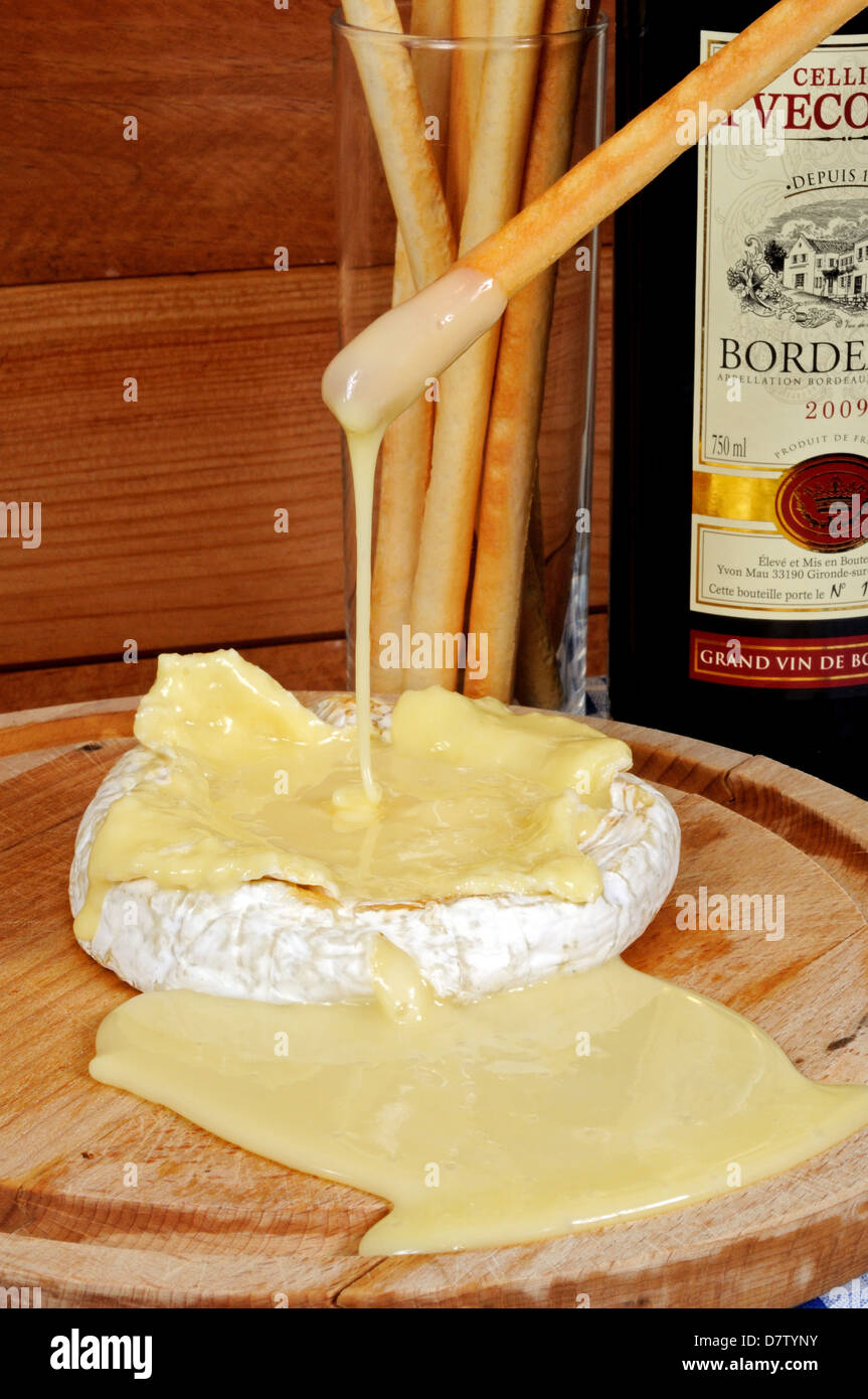 Baked whole French Camembert with Grissini breadsticks and a bottle of ...