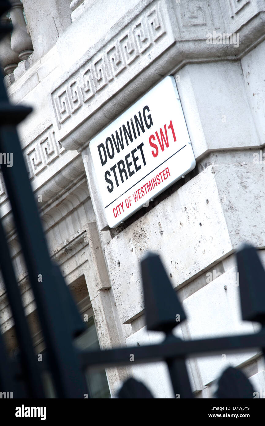 Road sign on wall signifying Downing Street with railings in foreground ...