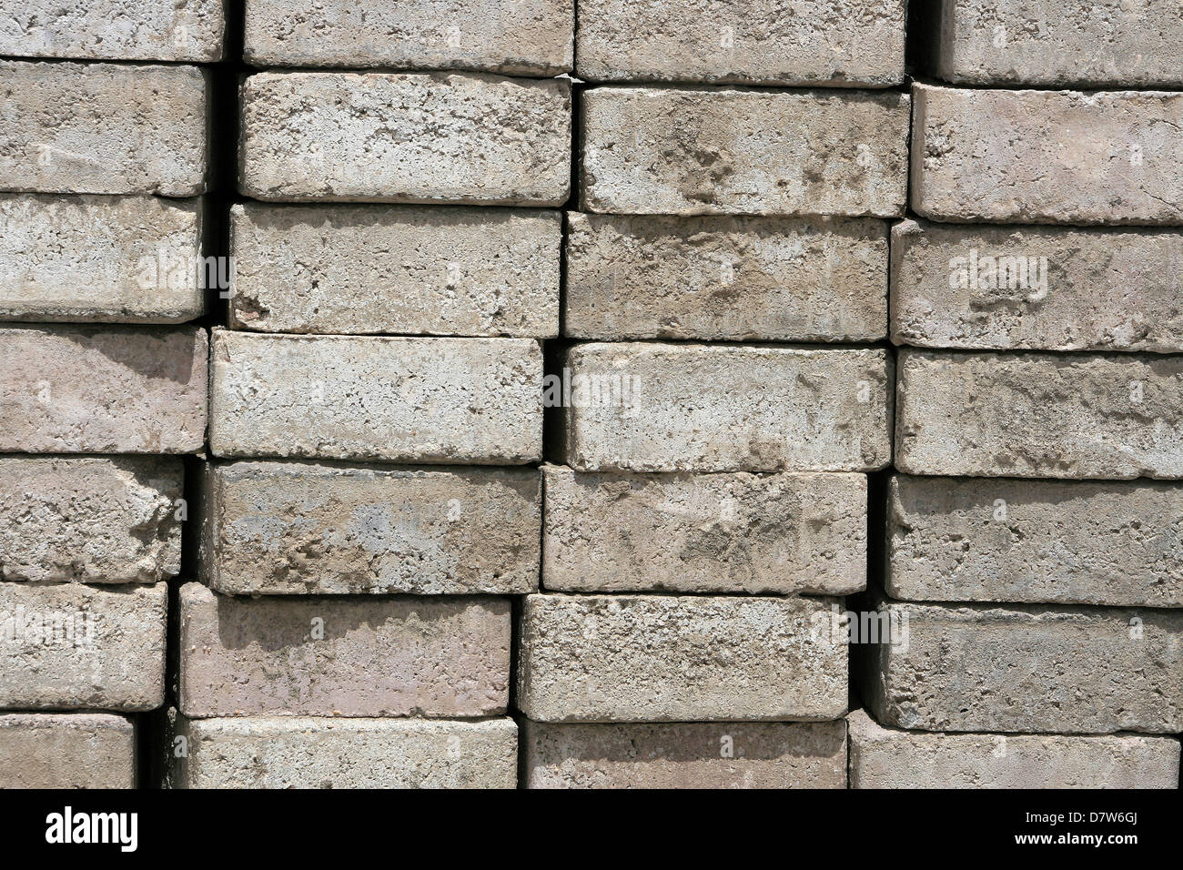 Small handmade gray bricks are stacked and ready for use at a ...