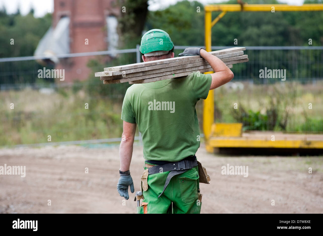 A construction worker is walking with shelves on his shoulder Stock ...