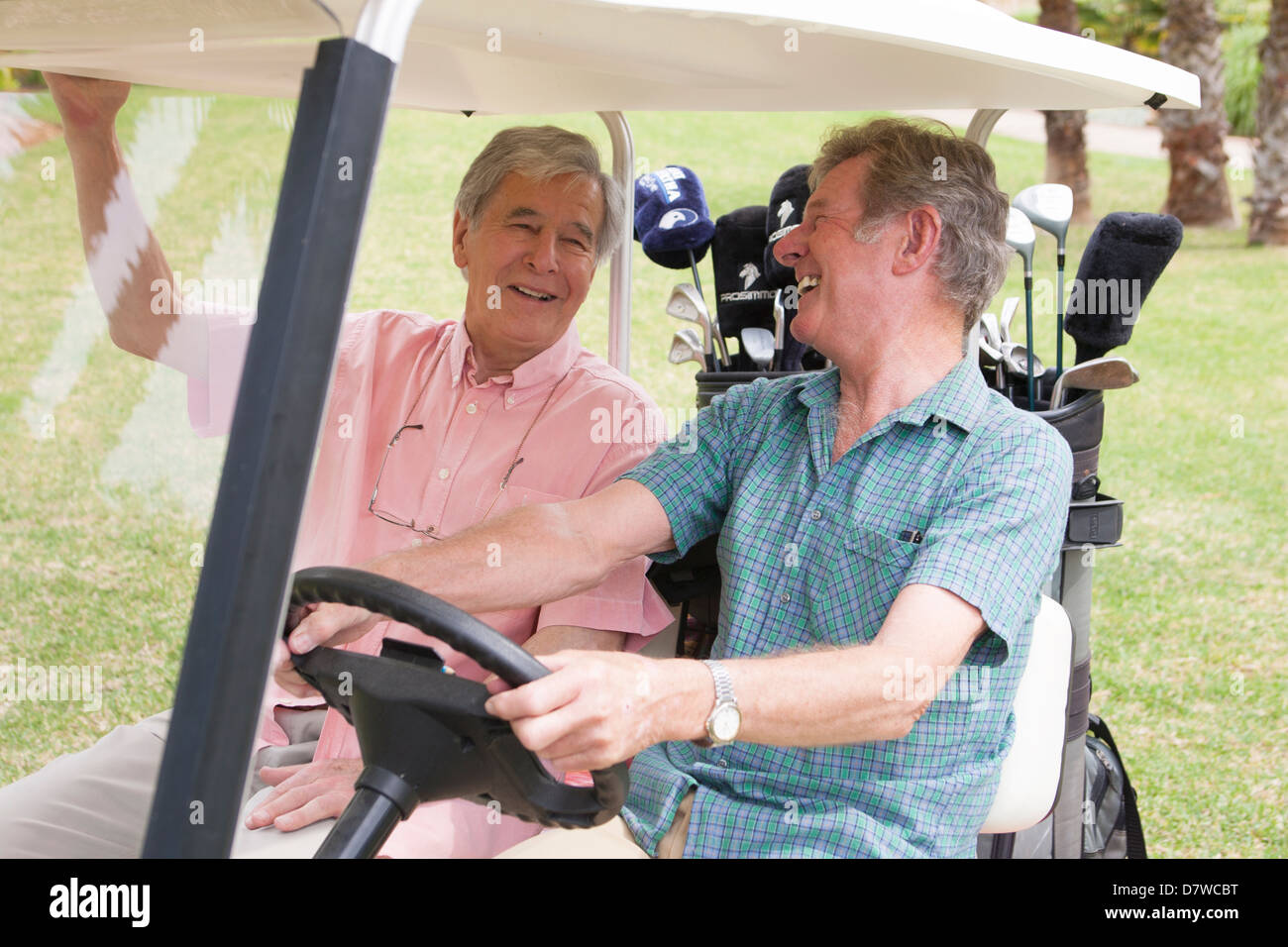 Two elderly men having a laugh on a golf buggy Stock Photo - Alamy