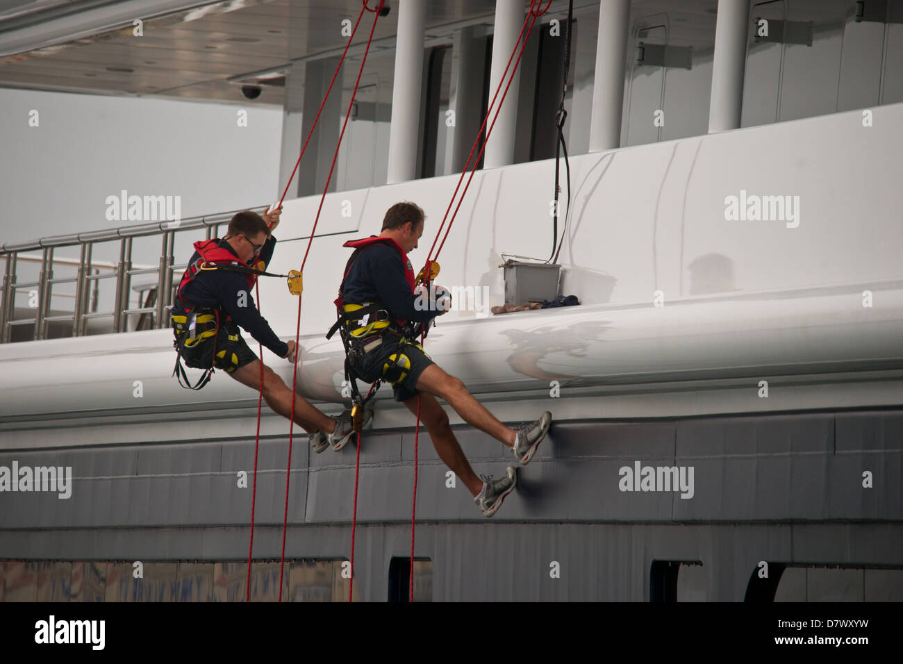 Two men abseiling down the side of a yacht to clean it Stock Photo - Alamy