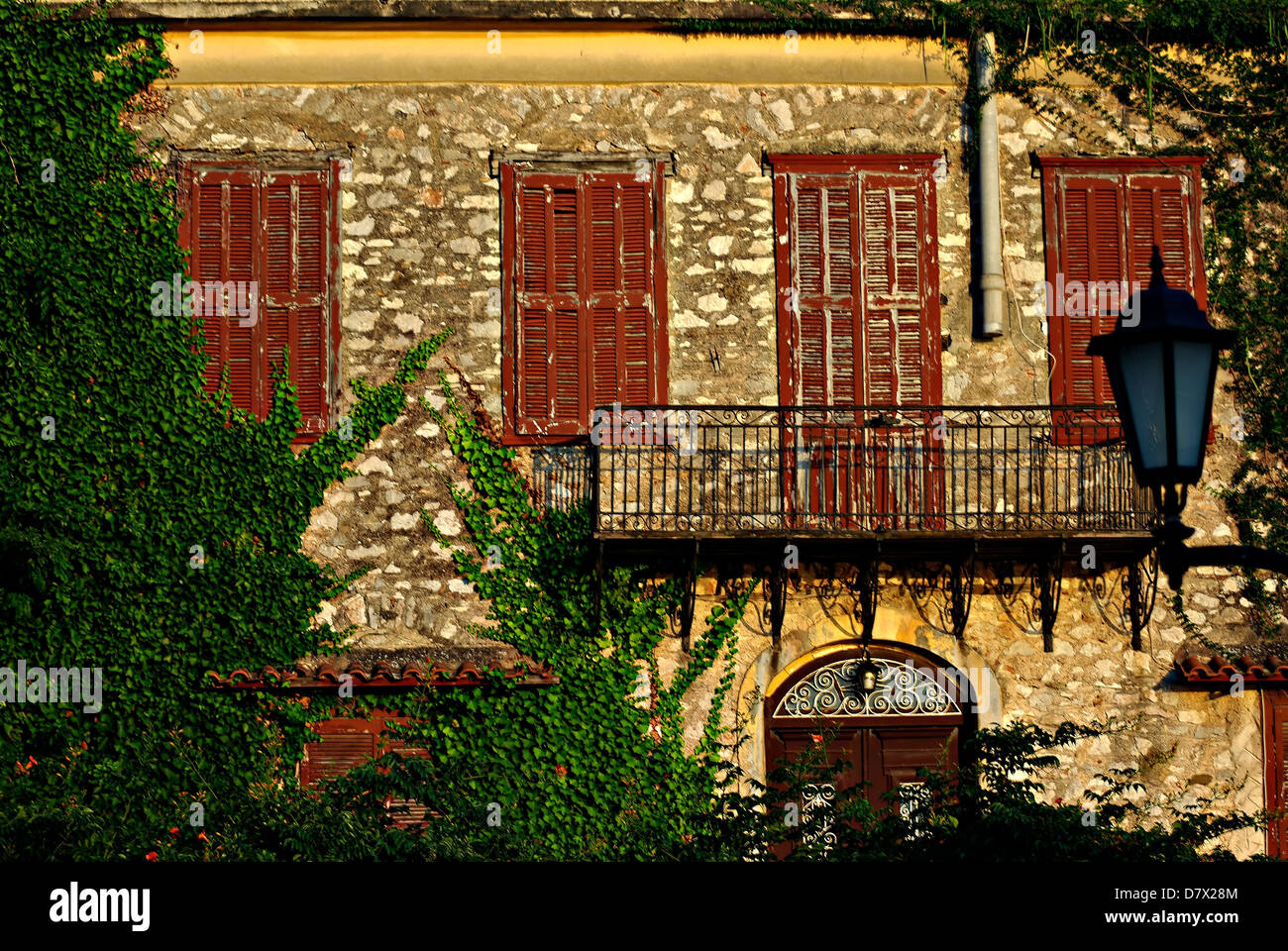 Neglected old house with rustic balcony and ivy on wall at afternoon ...