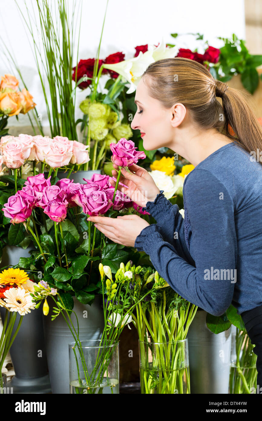 Female florist in flower shop or nursery presenting yellow roses Stock ...
