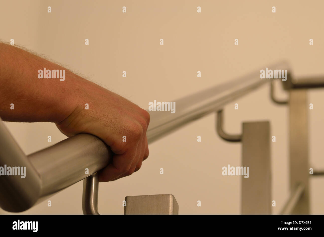 Close up image of a hand gripping a stainless steel stair handrail ...