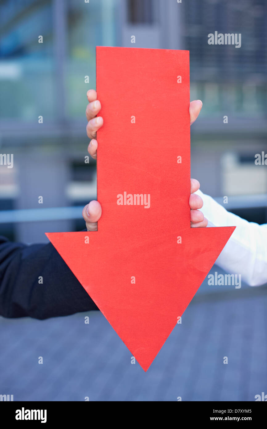 Hands holding a bold red arrow pointing down Stock Photo - Alamy