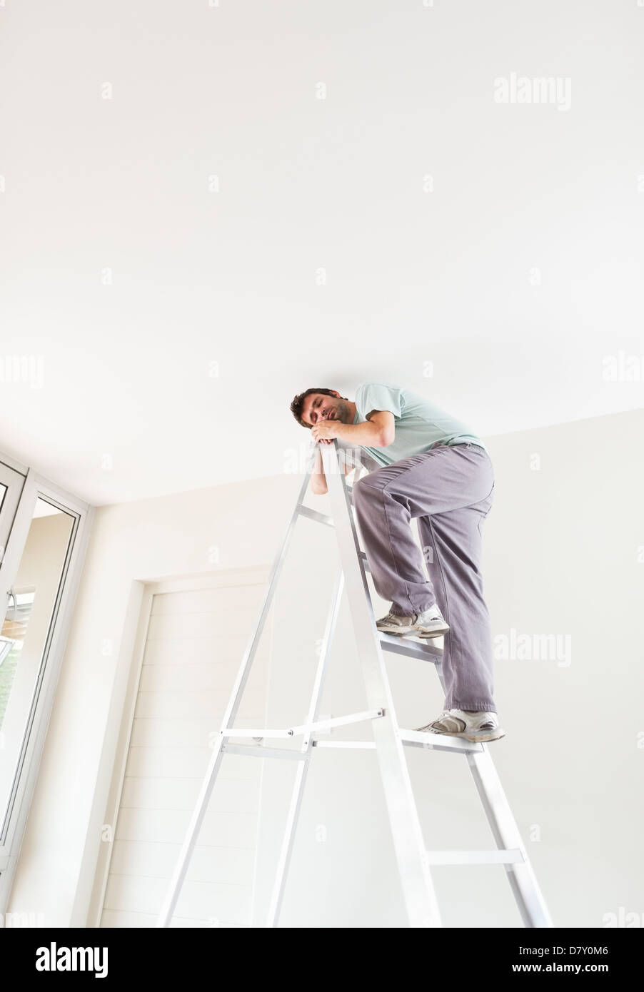 Man climbing ladder indoors Stock Photo - Alamy