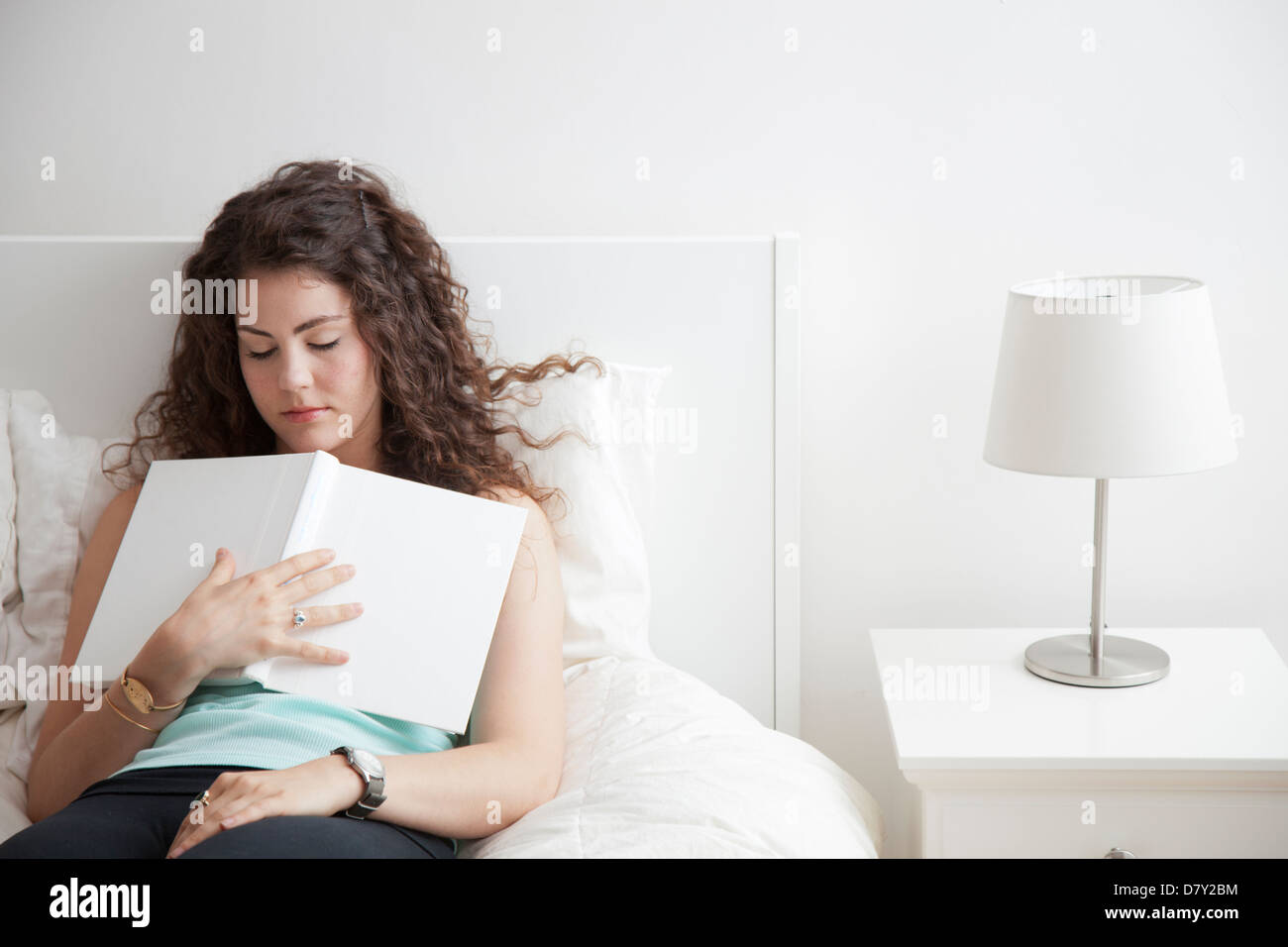 Caucasian woman sleeping in bed holding book Stock Photo - Alamy