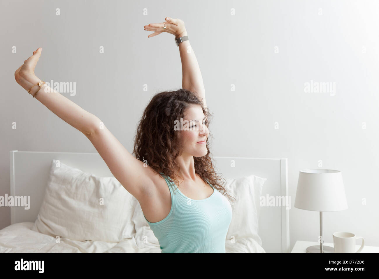 Caucasian woman stretching in bed Stock Photo - Alamy
