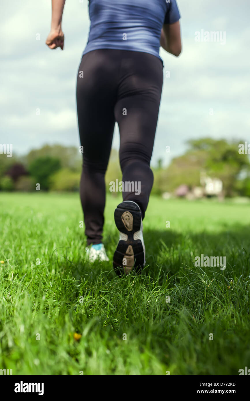 Rear view of a woman running on the grass Stock Photo - Alamy