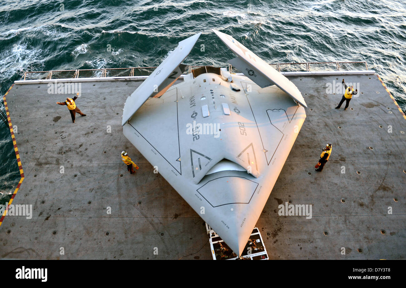 US Navy sailors move the X-47B Unmanned Combat Air System aircraft on the elevator for launch ...