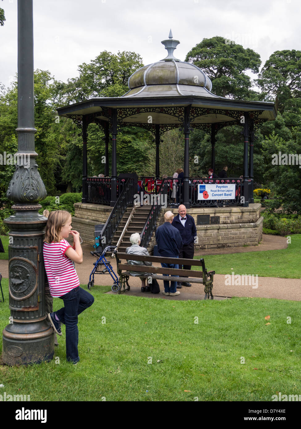 Young child /girl leaning against a lamp post with elderly people and ...