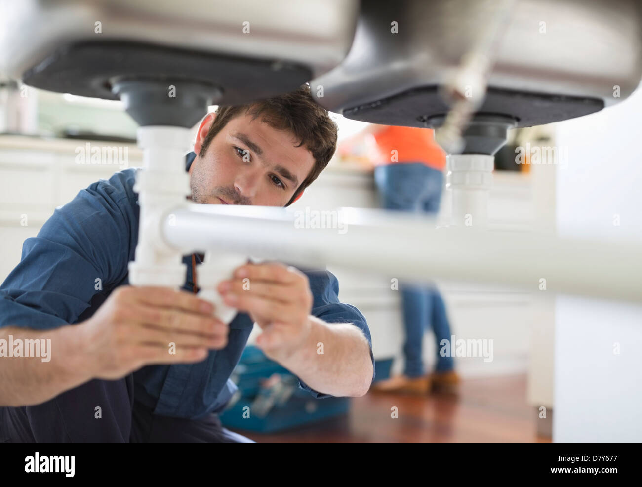 Plumber working on pipes under sink Stock Photo - Alamy