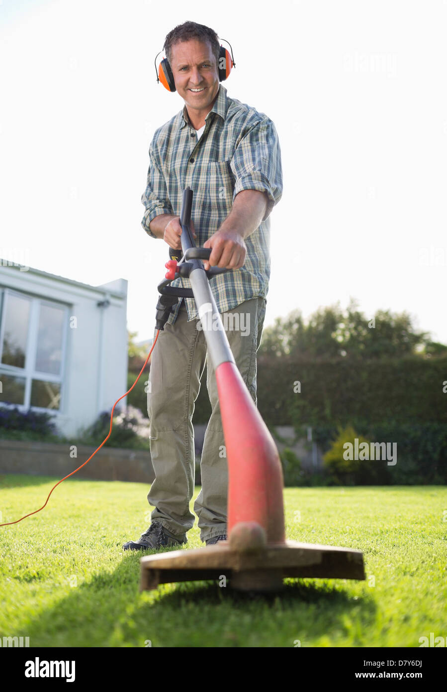 Man using weed whacker in backyard Stock Photo - Alamy