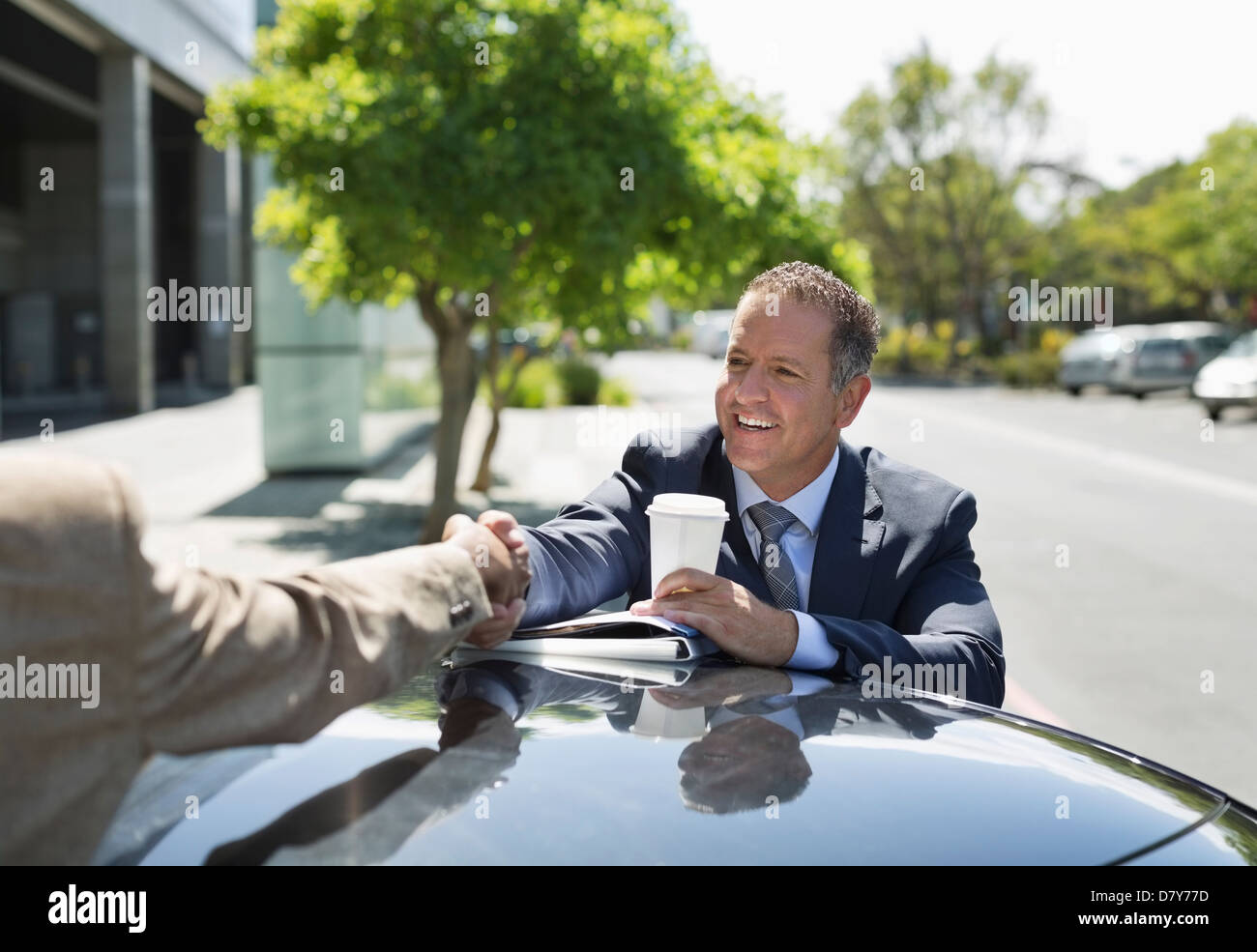 Businessmen shaking hands over car Stock Photo - Alamy