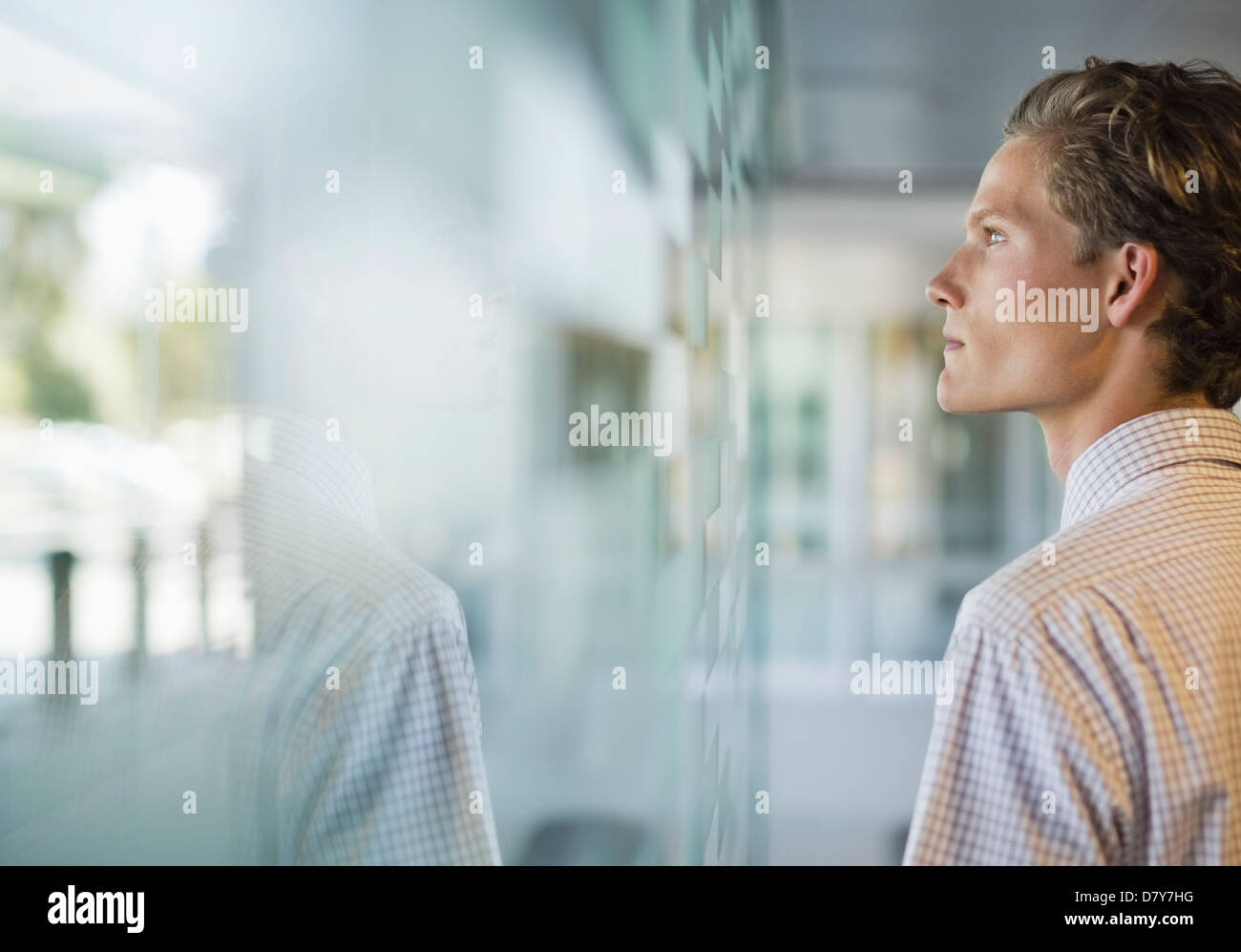 Businessman looking out office window Stock Photo - Alamy