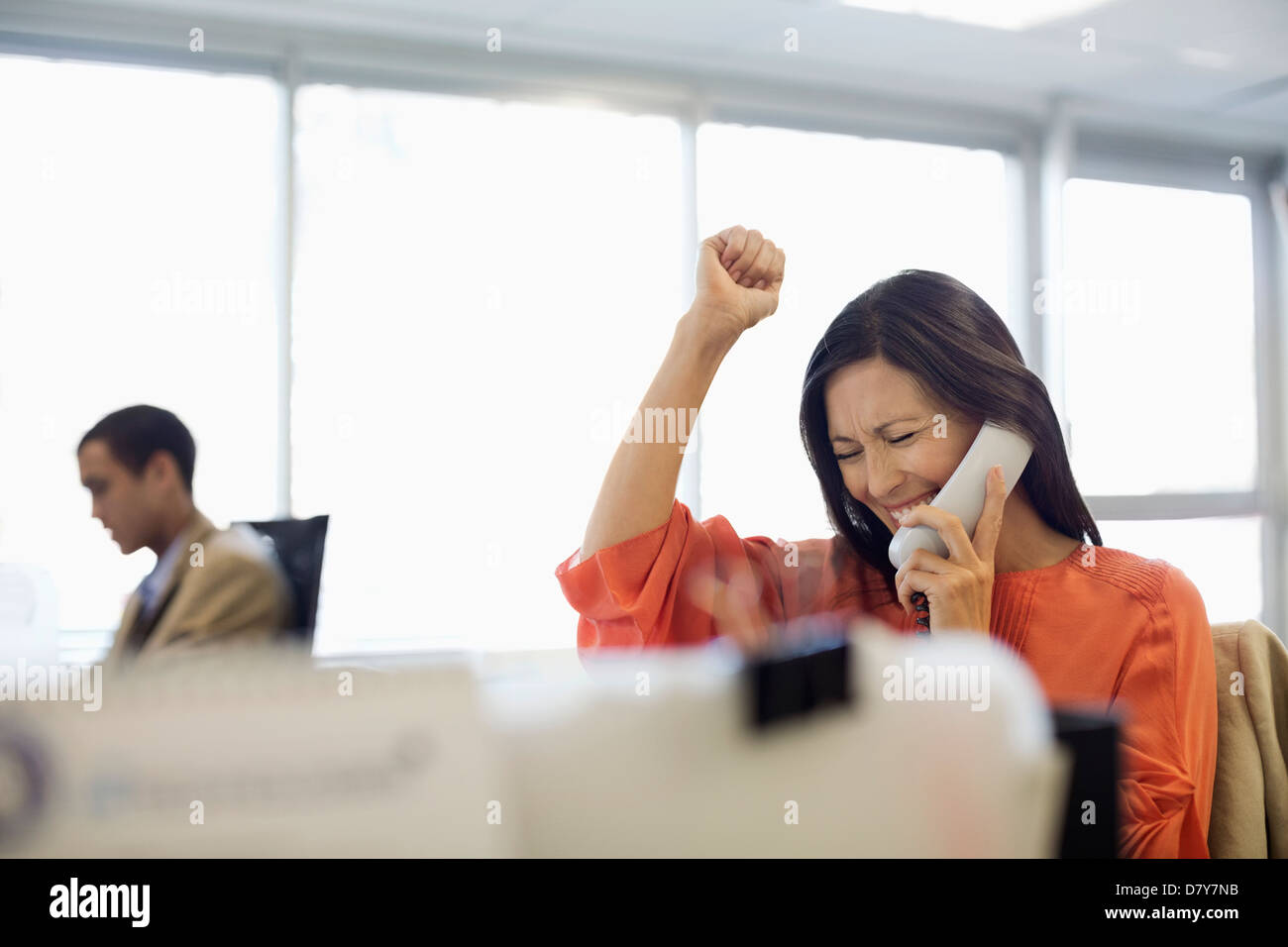 Businesswoman cheering at desk in office Stock Photo - Alamy