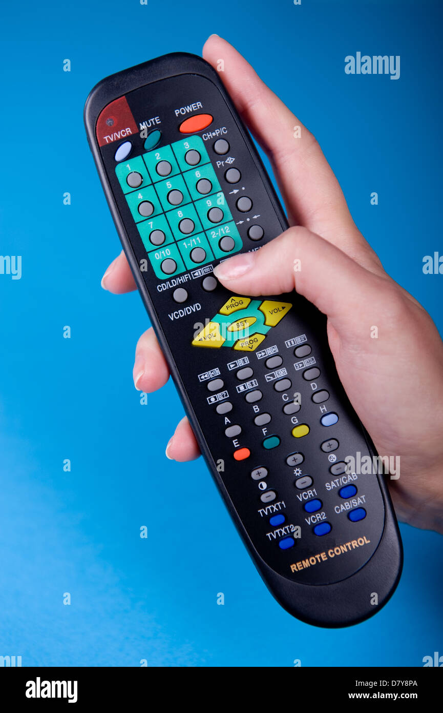 Female hand holding a multi-function television remote control against ...