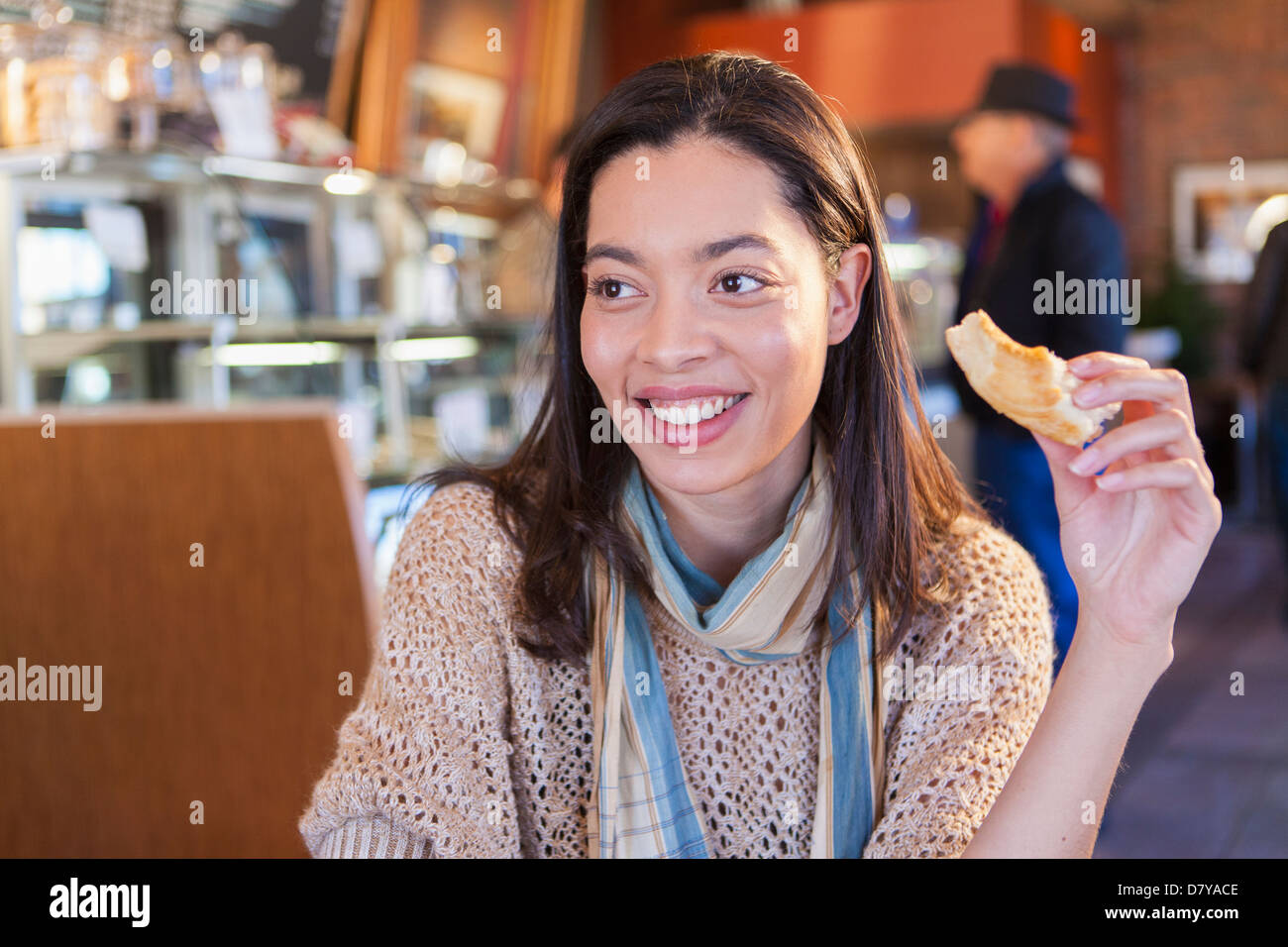 Mixed race woman eating in coffee shop Stock Photo - Alamy
