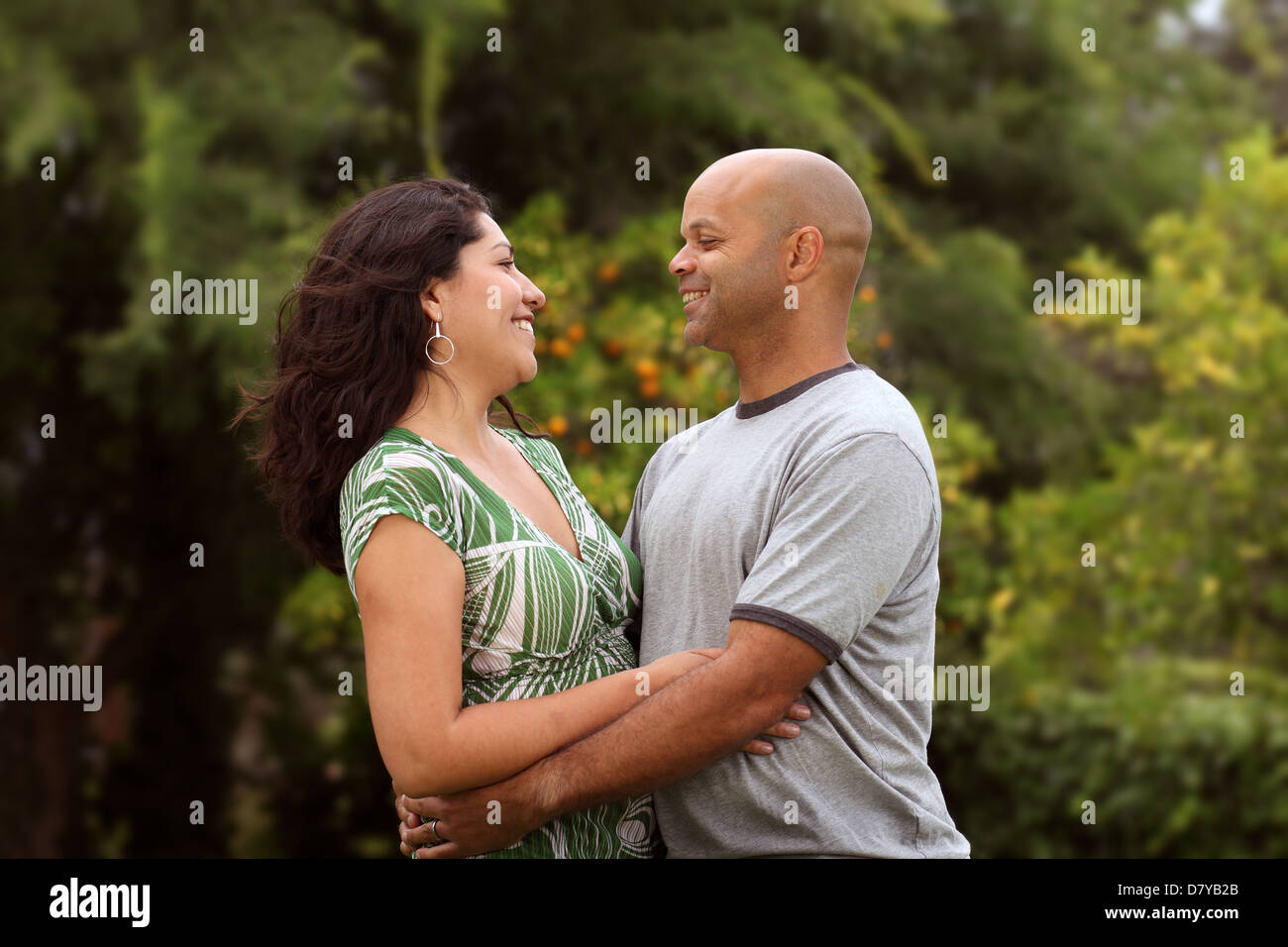 A happy mixed race couple relax outside in the back yard or garden ...
