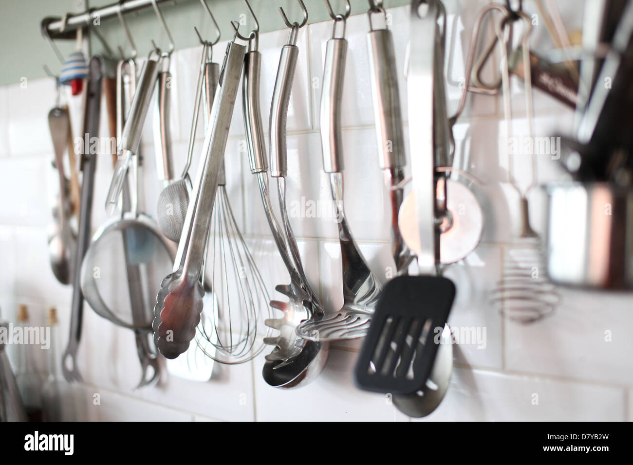 Cooking utensils hanging from a rack in the kitchen Stock Photo - Alamy