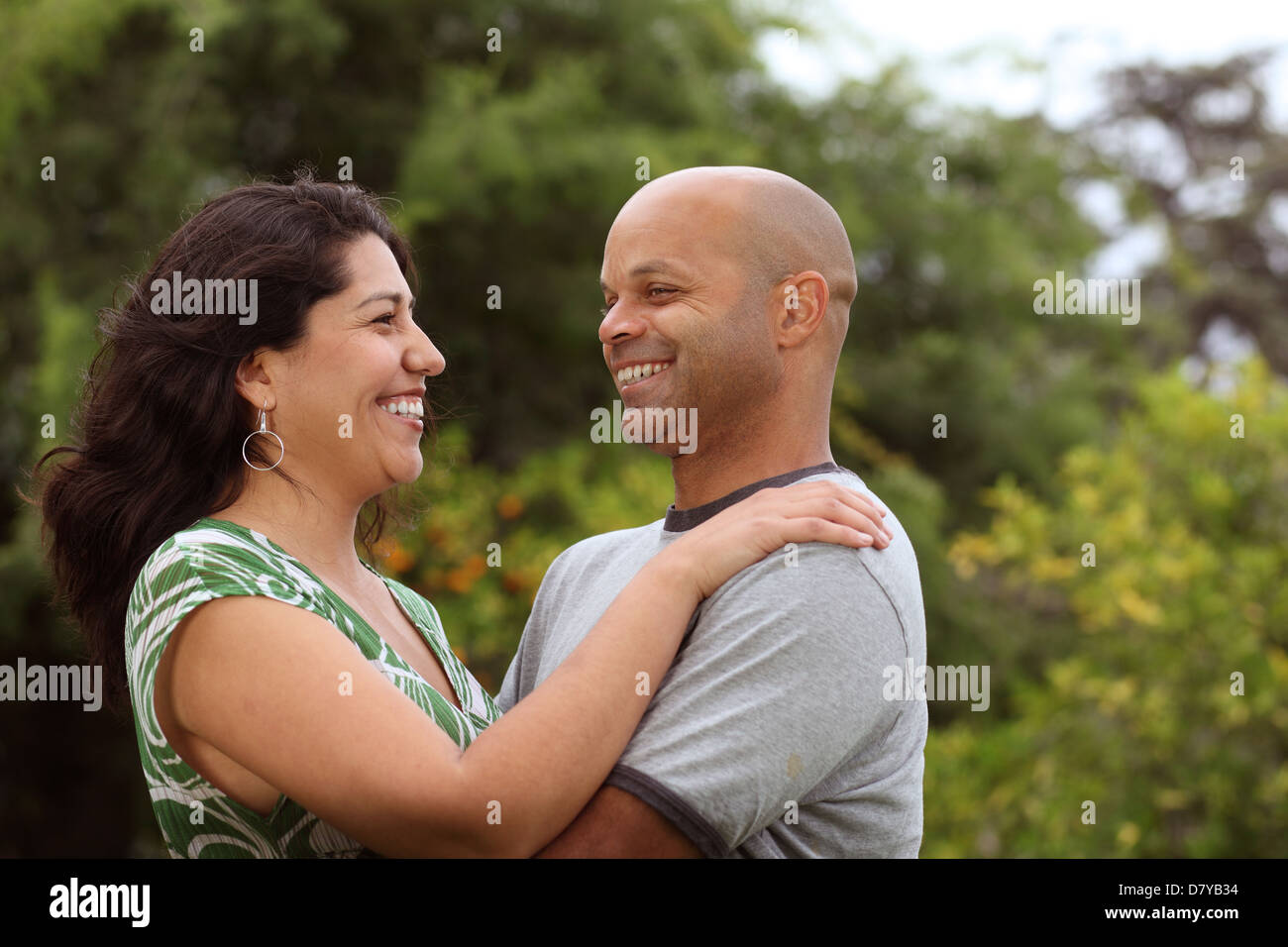 A happy mixed race couple relax outside in the back yard or garden ...