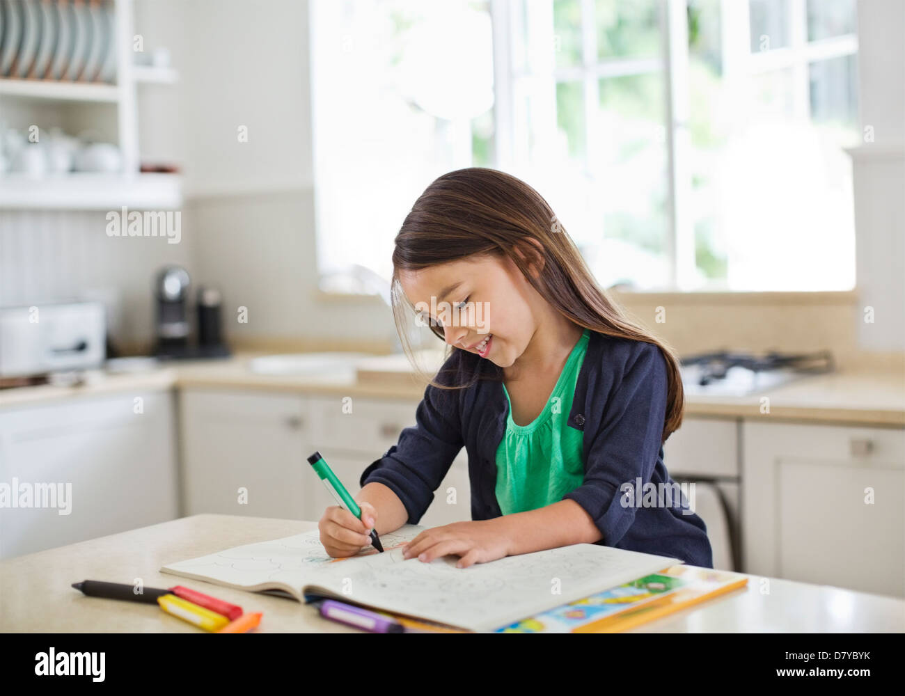 Girl using coloring book in kitchen Stock Photo - Alamy