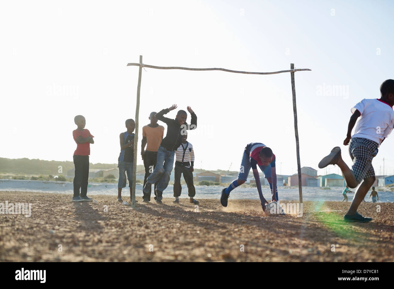 Boys playing soccer together in dirt field Stock Photo - Alamy