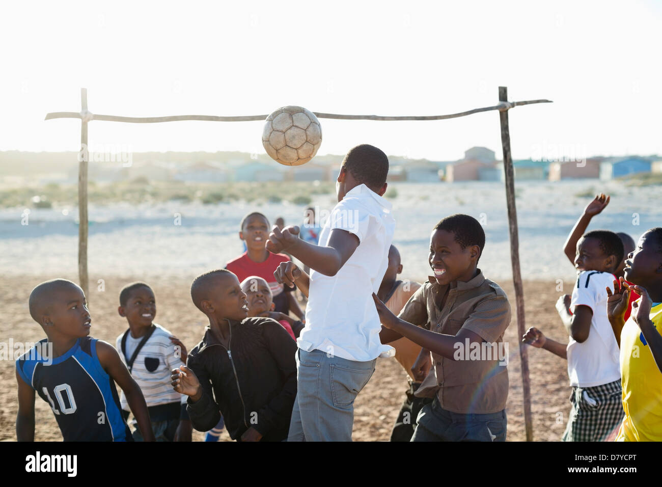 Boys playing soccer together in dirt field Stock Photo - Alamy