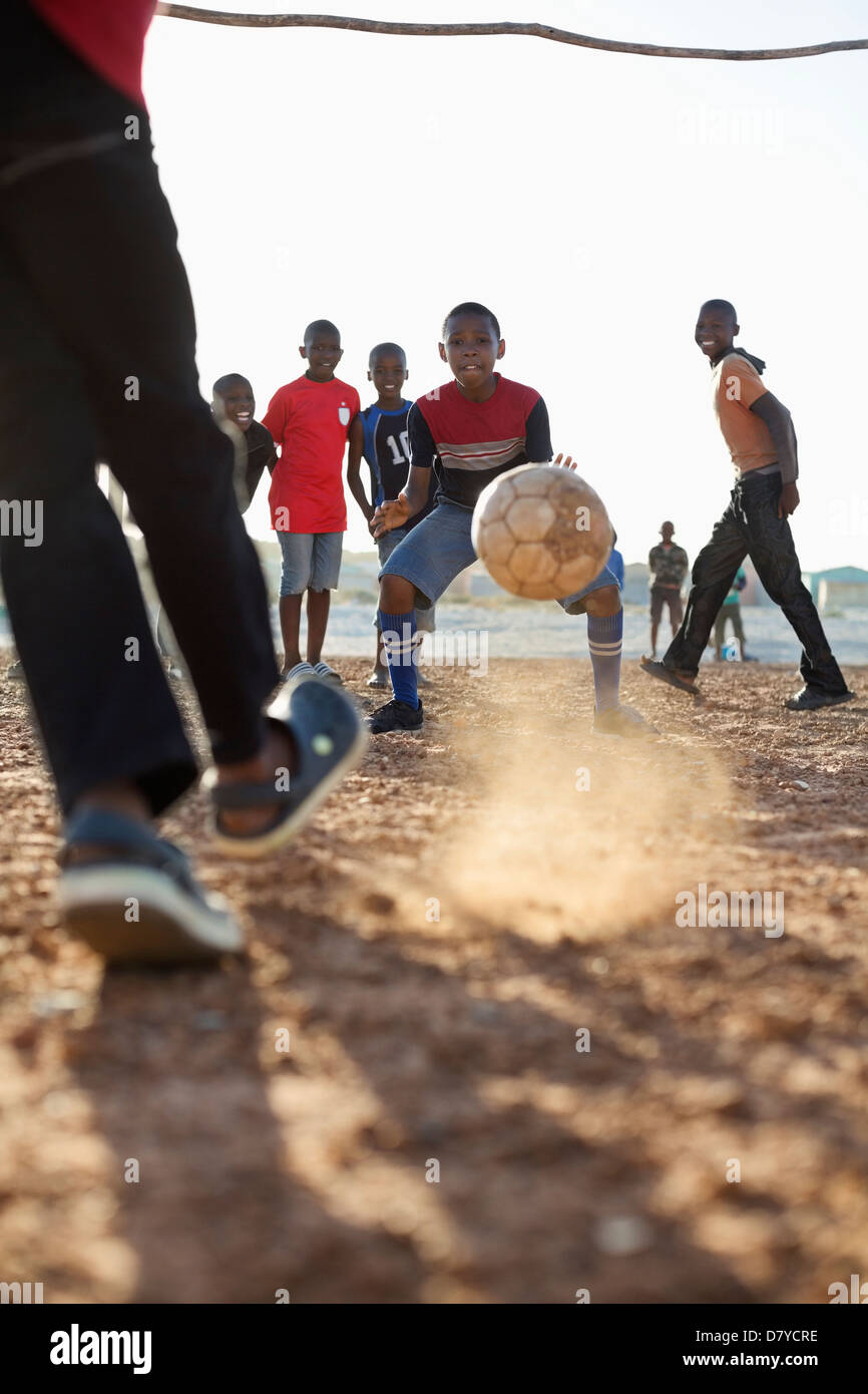 Boys playing soccer together in dirt field Stock Photo - Alamy
