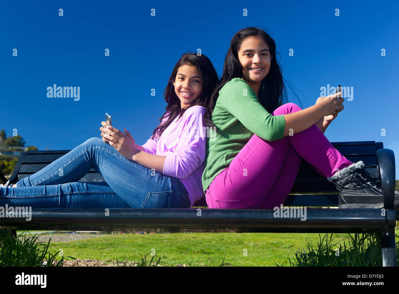 Hispanic teenage girls sitting on park bench Stock Photo - Alamy