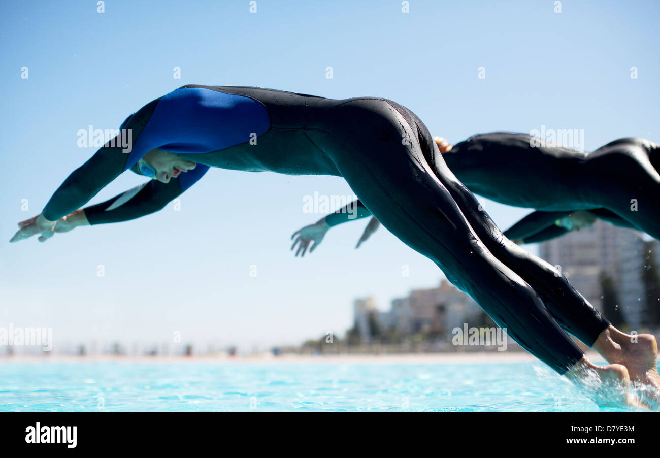 Triathletes diving into swimming pool Stock Photo - Alamy